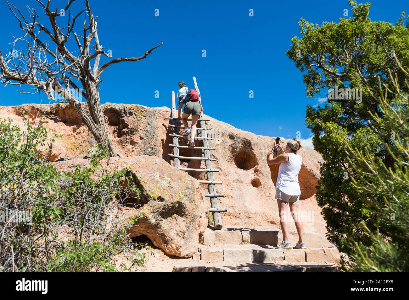 Family exploring the Tsankawi Ruins in New Mexico climbing up steps ...