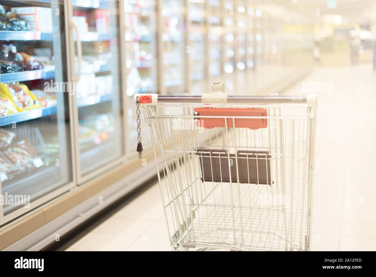Empty red shopping cart in supermarket interior. Copy space ...