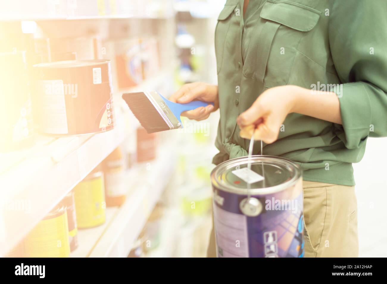 Woman shopping in hardware store. Girl is choosing paint in paint store ...