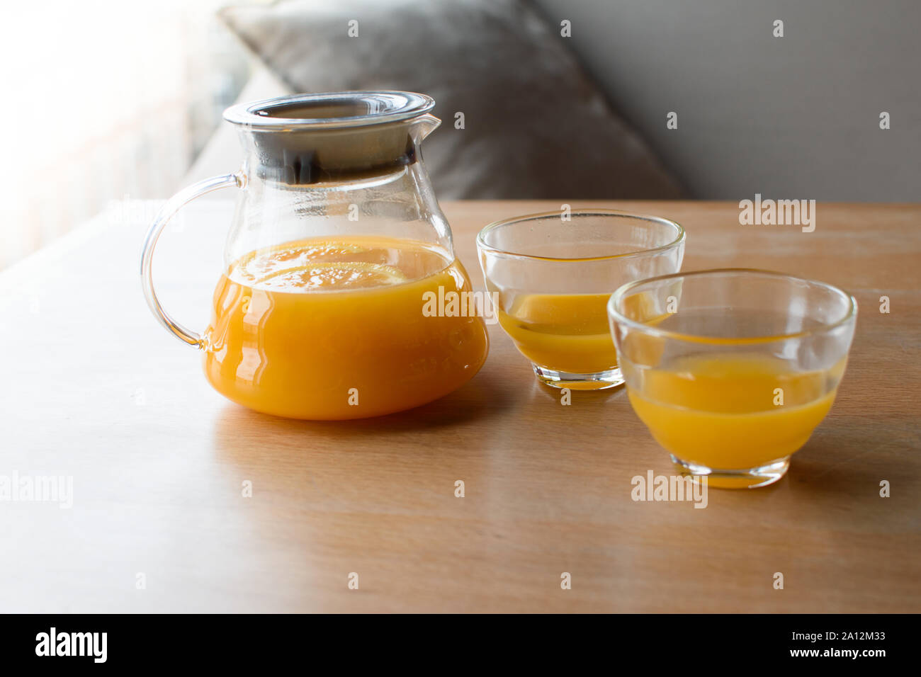 Teapot of orange fruit tea and two glass cups in a wooden table in a ...