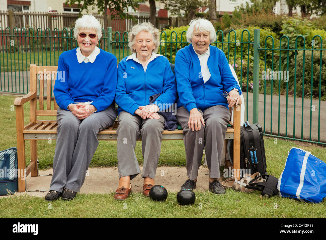 Three people sitting on a park bench hi-res stock photography and ...