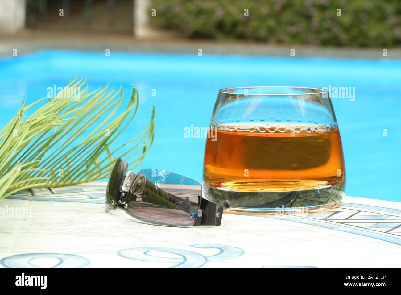 A glass of whiskey on a table close to the swimming pool Stock Photo ...