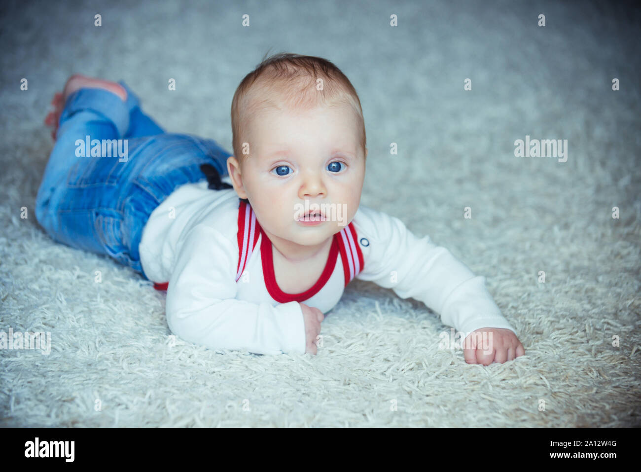 Baby with blue eyes on adorable face. Infant crawl on floor carpet ...