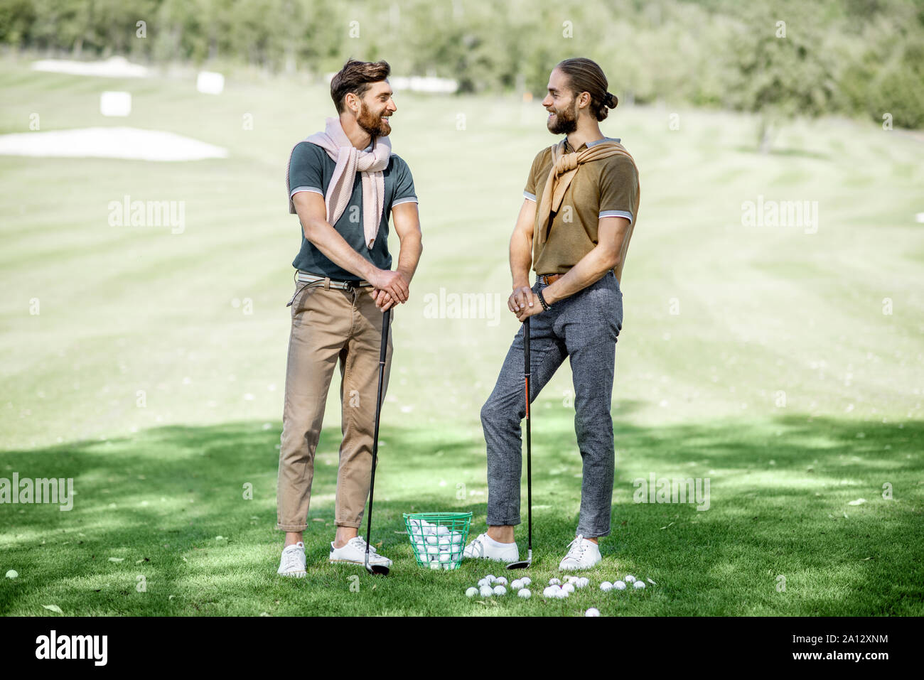 Two male best friends standing with playing equipment on a golf course ...