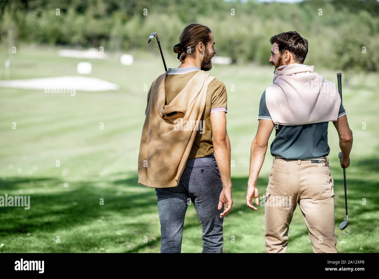 Two male best friends walking with golf equipment on beautiful playing ...