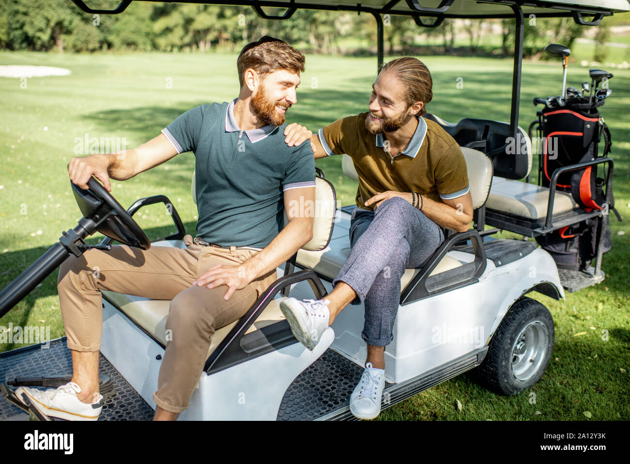 Two male best friends having fun while driving a golf car on the ...
