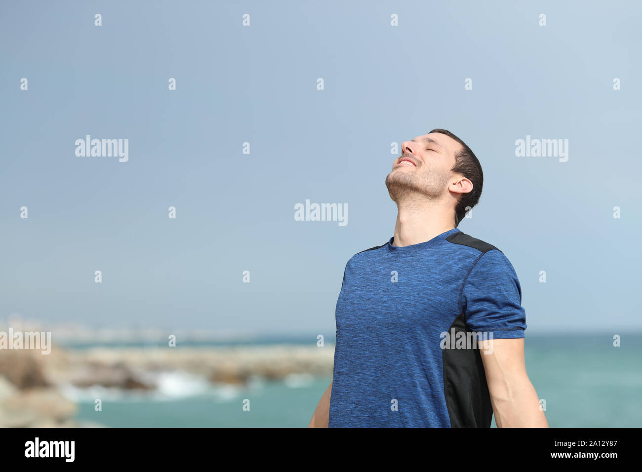 Happy runner breathing deeply fresh air on the beach before sport Stock ...