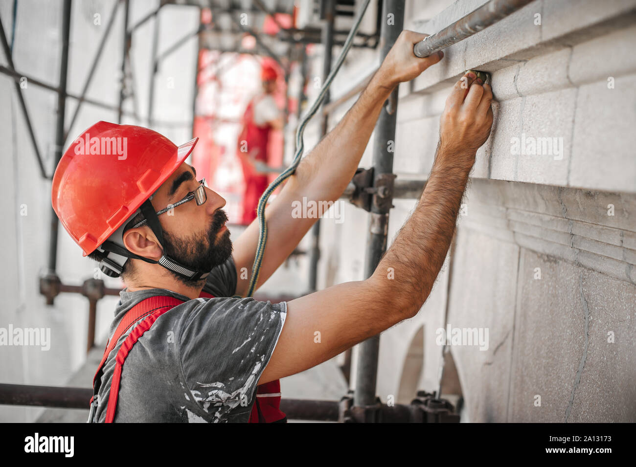 Man worker standing on scaffolding, perform work on the restoration of ...