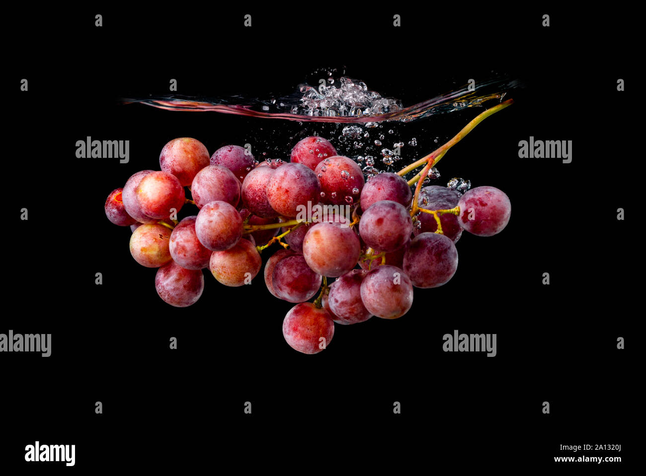Isolated Red grapes splashing and sinking in water on black background ...