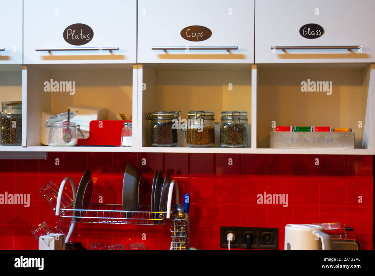 Kitchen interior at home or small office. Red tile wall and white shelf ...