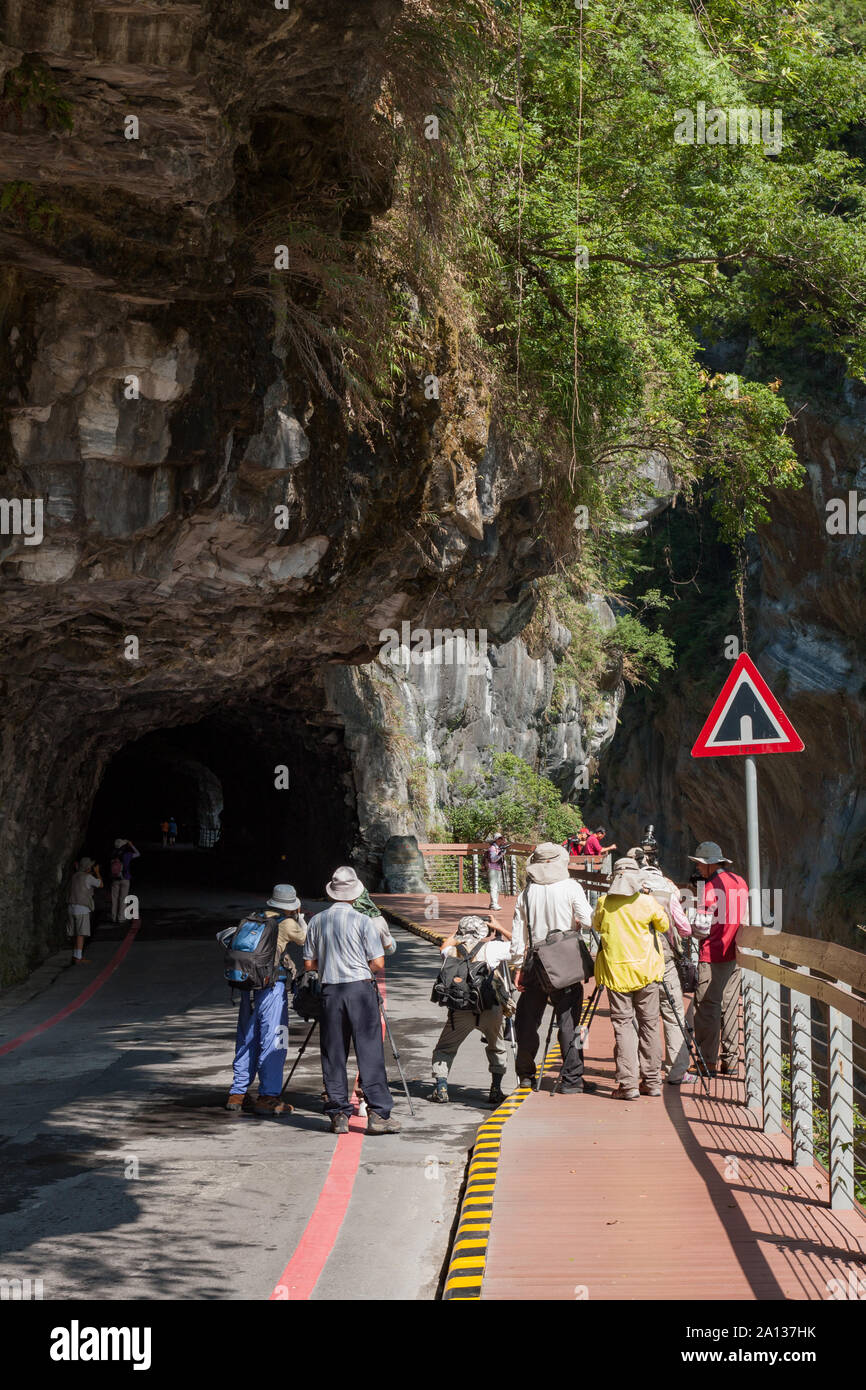 A group of photographers trying to take shot of cliffside tunnel on ...