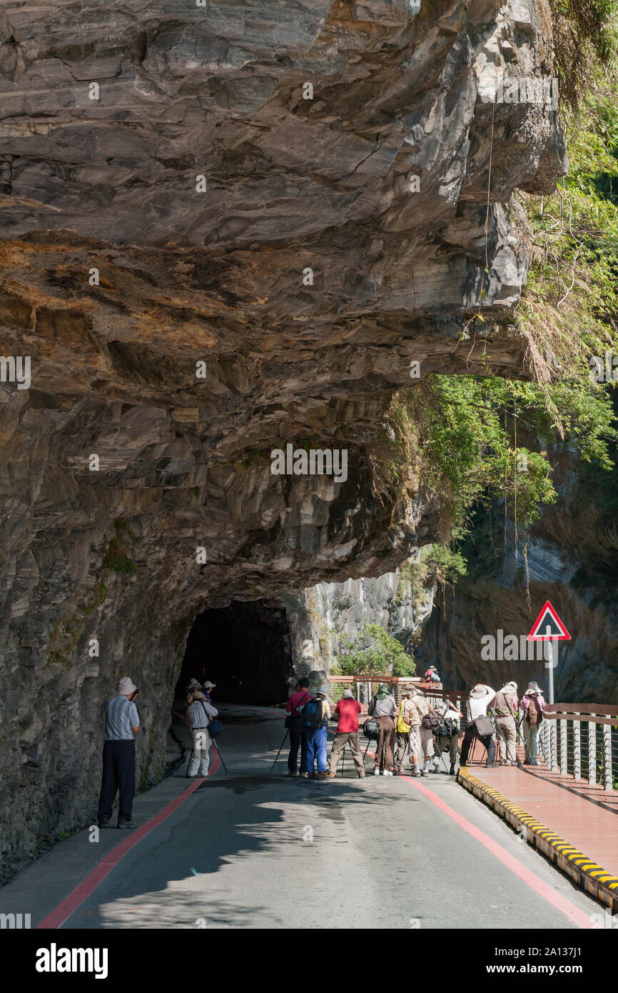 A group of photographers trying to take shot of cliffside tunnel on ...