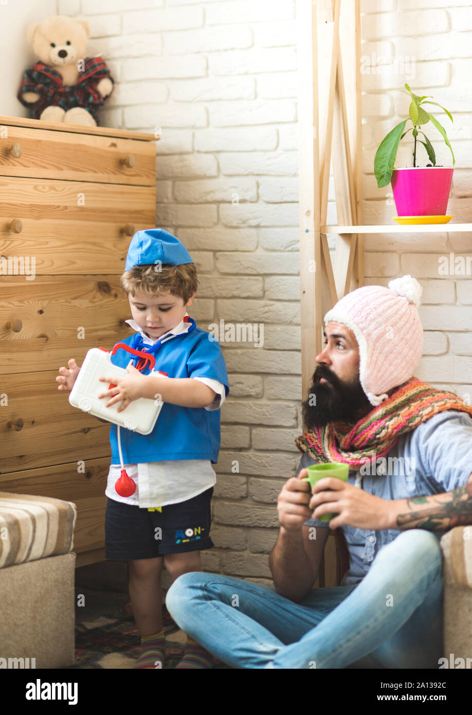 Boy with first aid kit over white brick wall. Father and son playing ...