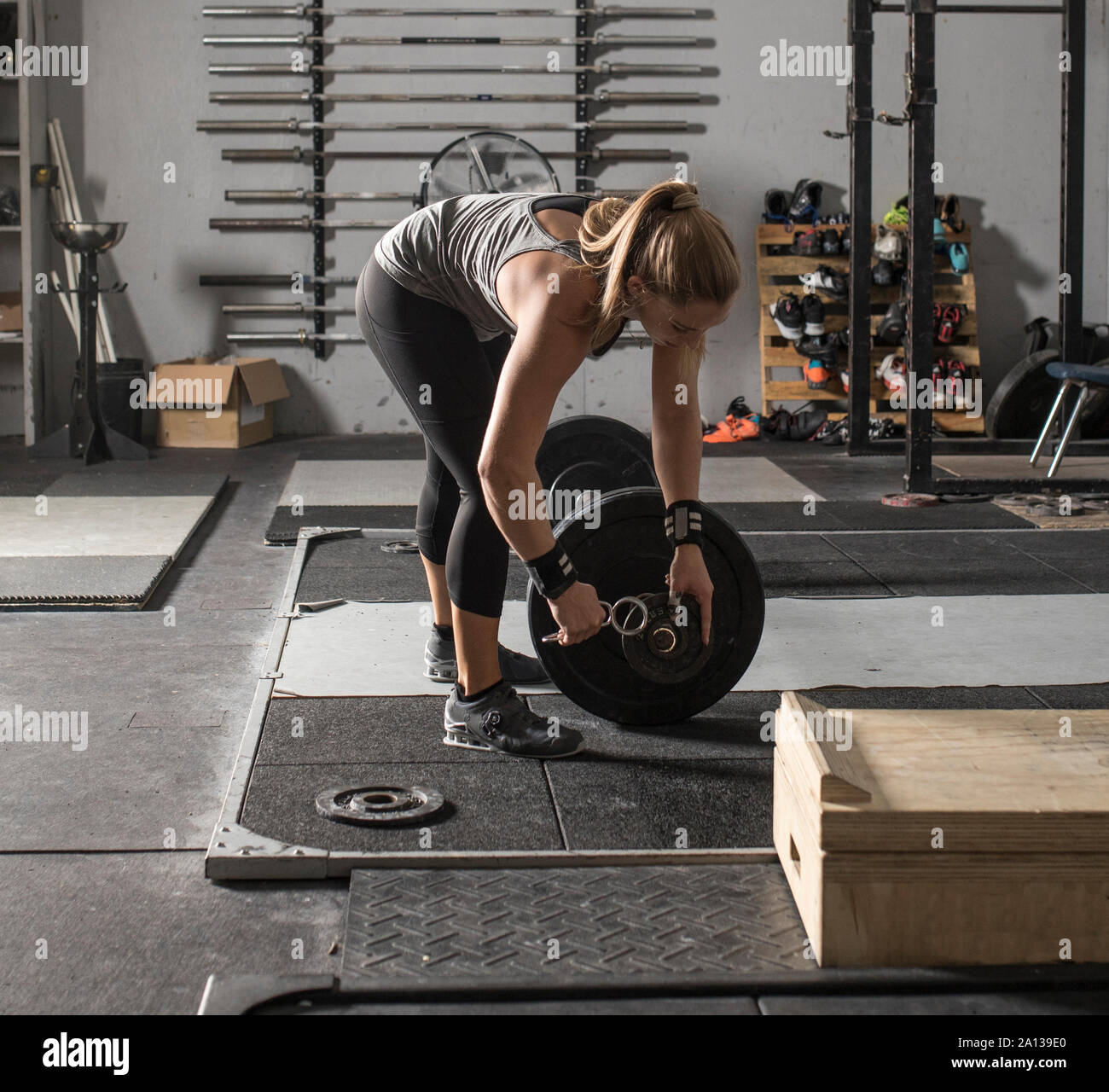 Young strong woman loading weights onto barbell in a gym Stock Photo ...