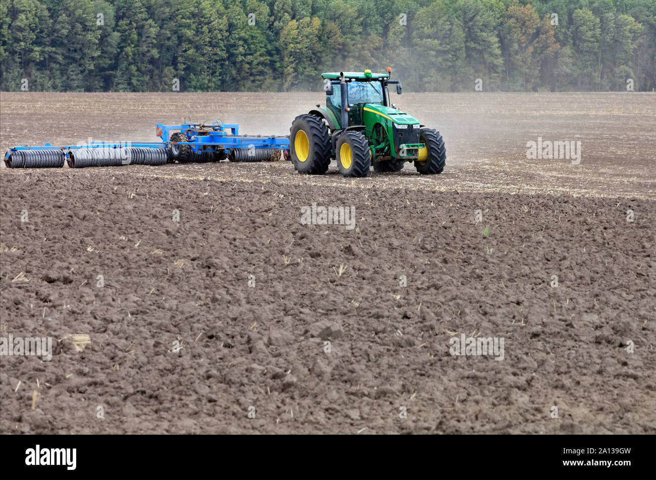 The tractor in the field shallow plow the soil with metal discs after ...