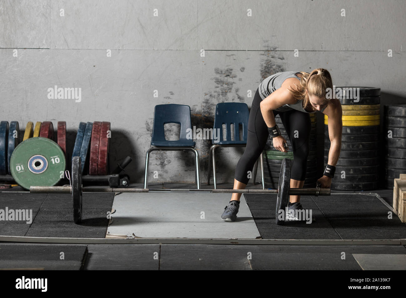 Young strong woman loading weights onto a barbell in a gym Stock Photo ...