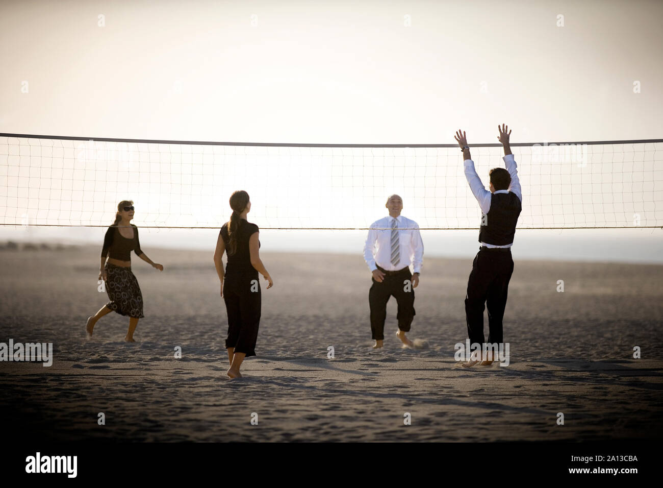Two couples are playing volleyball on the beach Stock Photo - Alamy