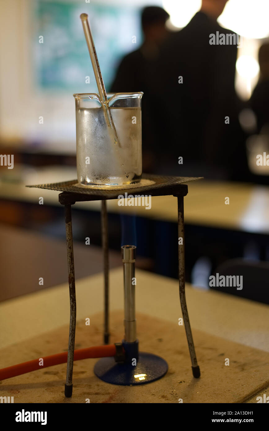Heating water in a beaker with a gas burner in a school science lab ...