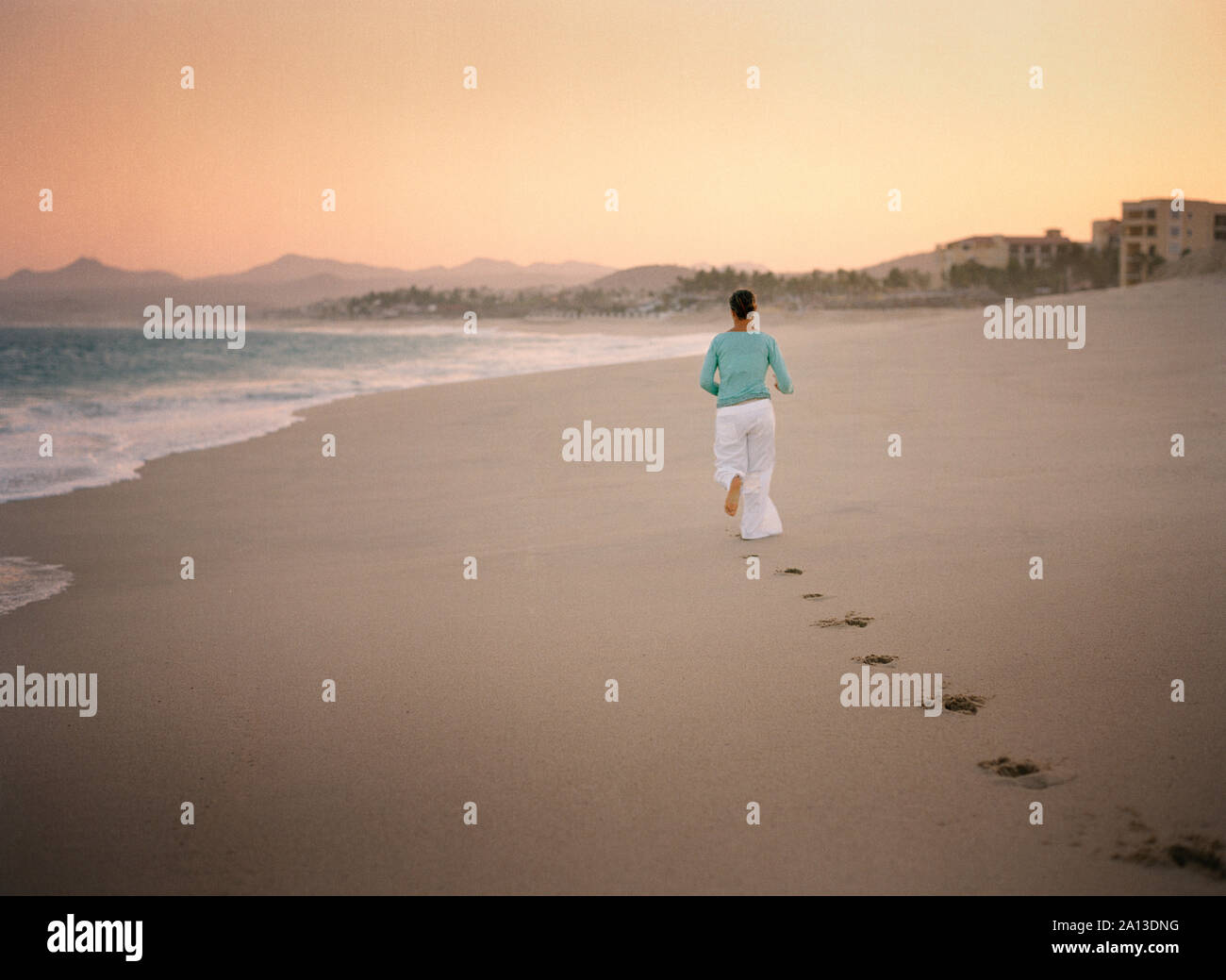 Footprints of a woman are left behind as she walks on the beach Stock ...