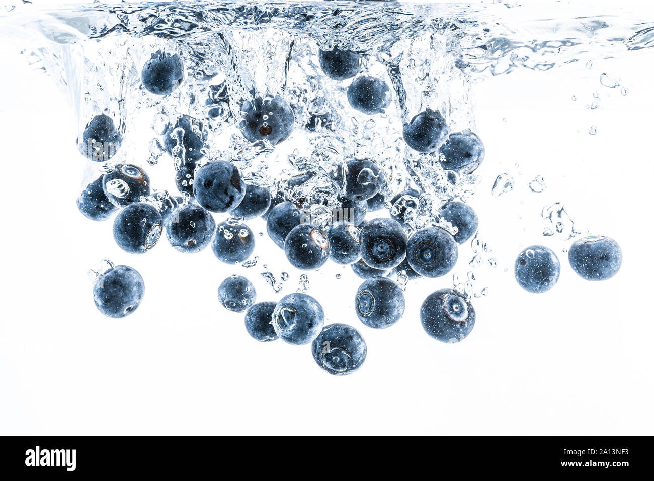 Fresh blueberries falling in water on white background. Fruits ...