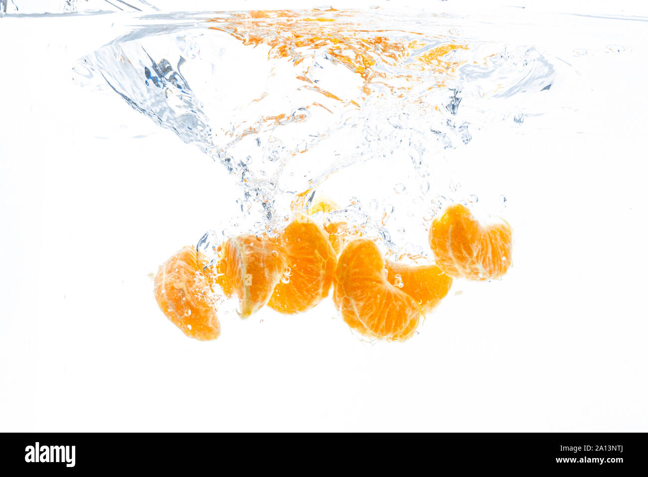 Isolated falling orange segments into water. Peeled pieces of orange ...