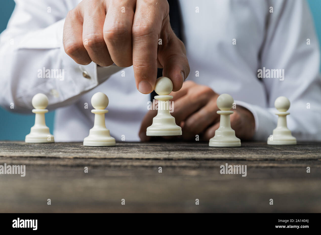 Hand of a businessman positioning white pawn chess piece in front of ...