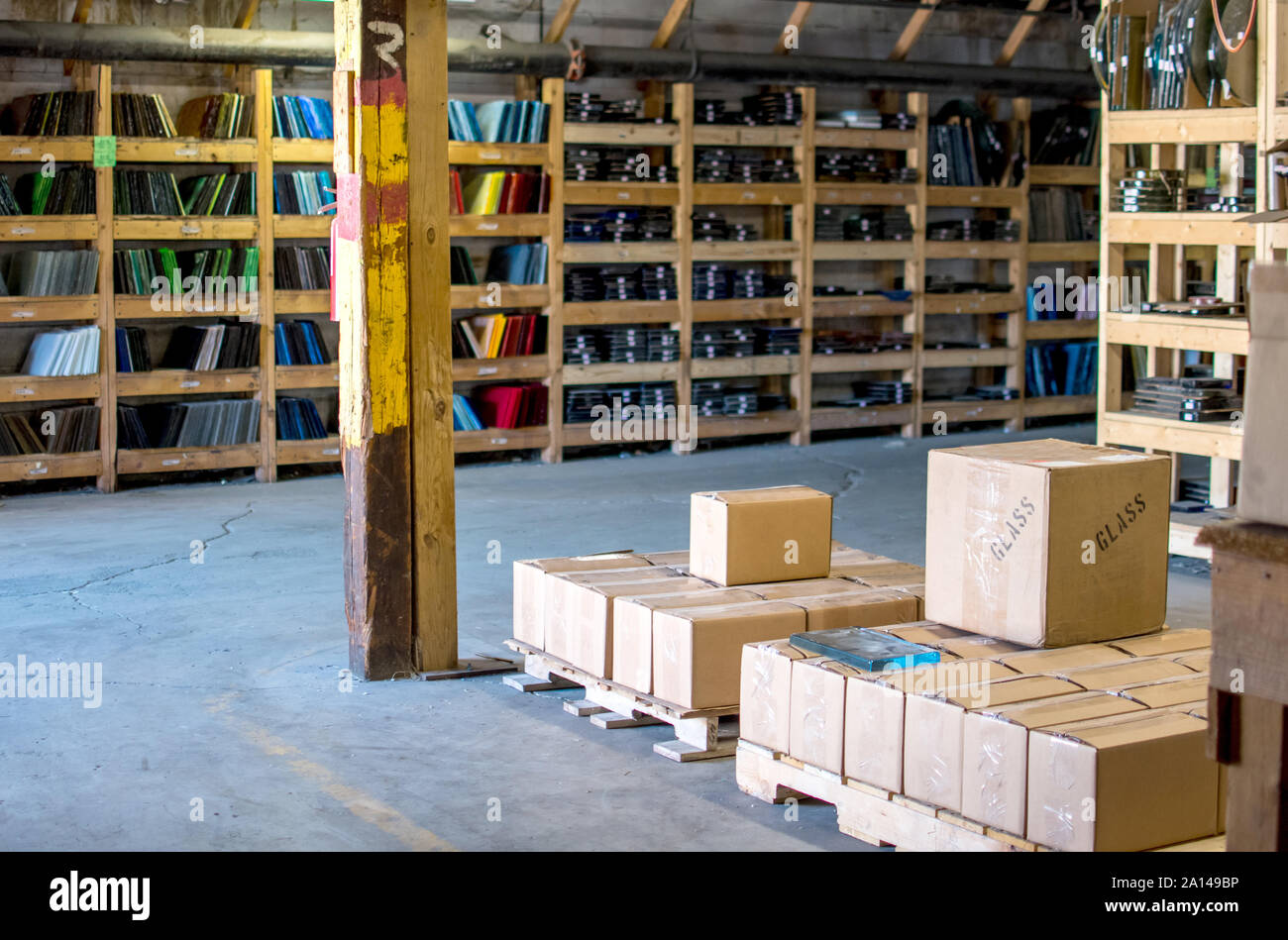 Fragile boxes of glass sit on wood pallets in a glass factory loading ...