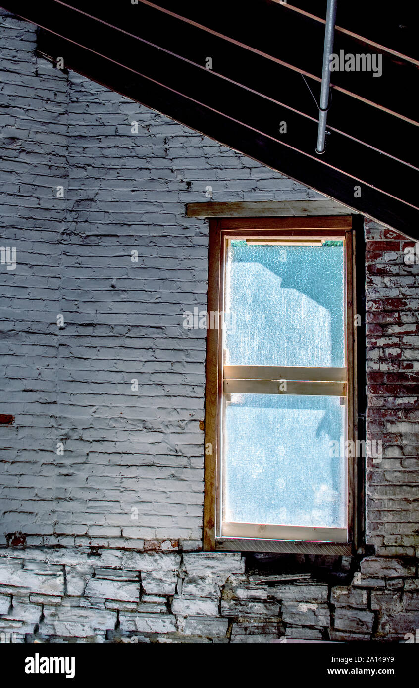 a window lit with sunlight, is under the attic eves in this old, brick ...