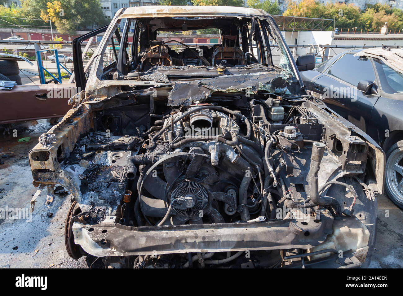 A burnt car after a fire or an accident in a parking lot covered with ...
