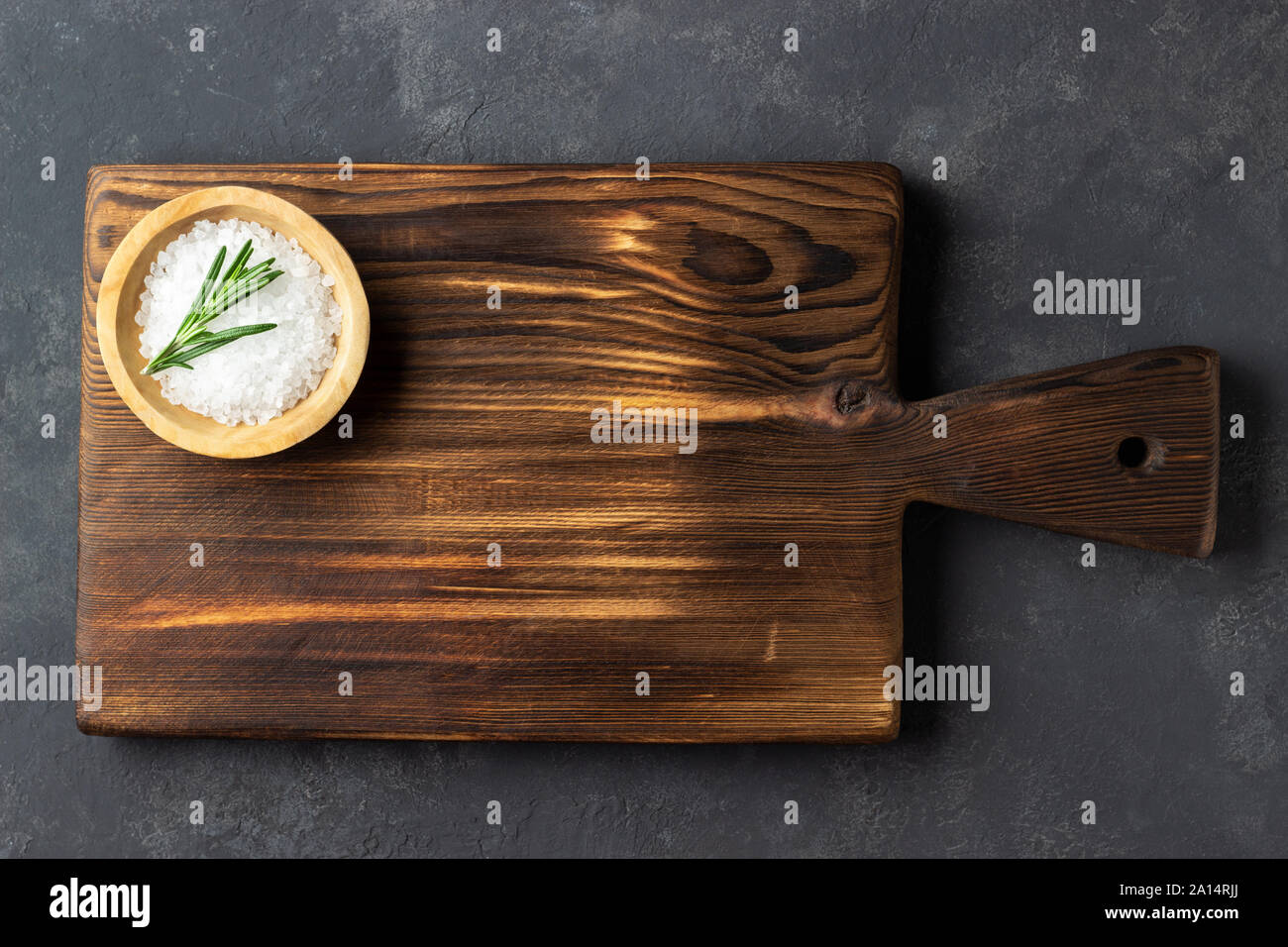 Cooking concept. Vintage cutting board with salt on dark stone ...