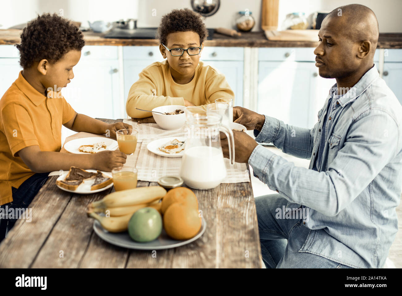 Dad and his son trying to persuade the older one to having breakfast ...