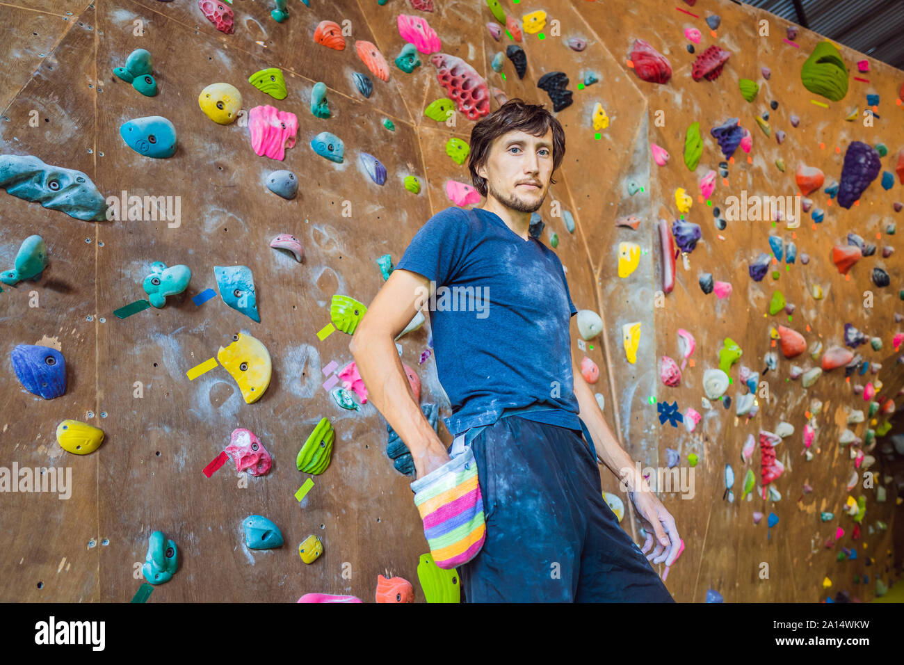 Muscular man practicing rock-climbing on a rock wall indoors Stock ...
