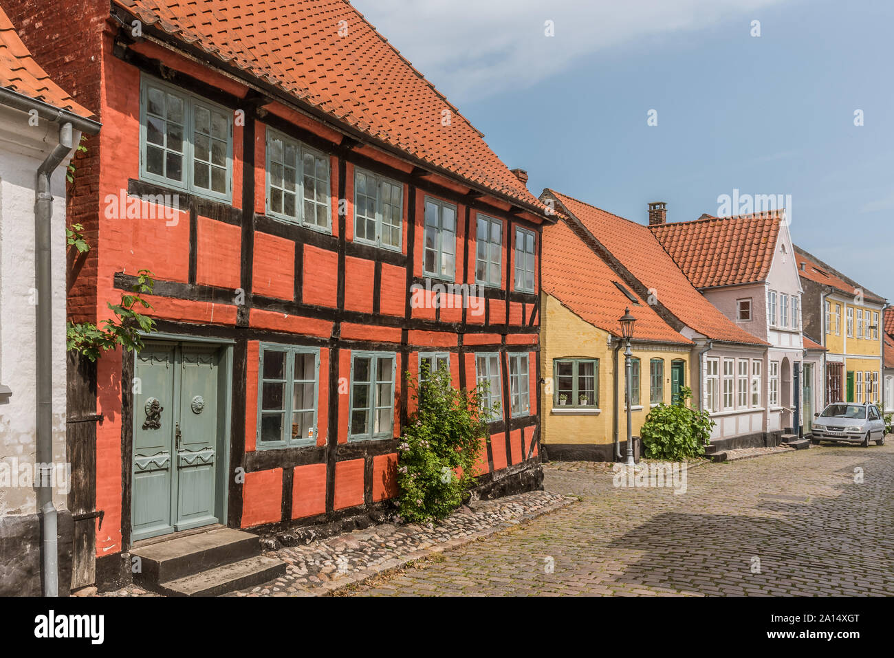 the facade of a red two stock half-timbered house in a cobbled street ...