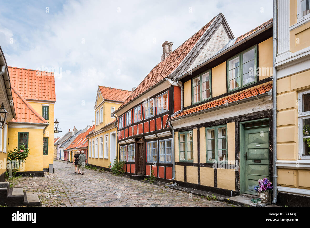 two persons walking at the end of an idyllic cobblestone street with ...
