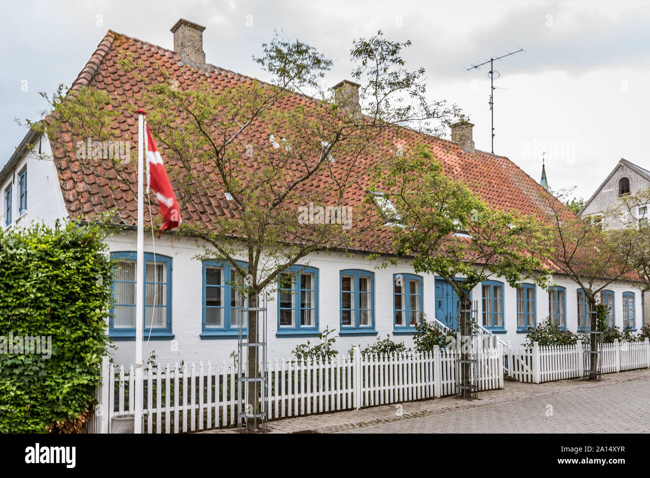 the danish flag outside a house with blue windows and a white fence in ...