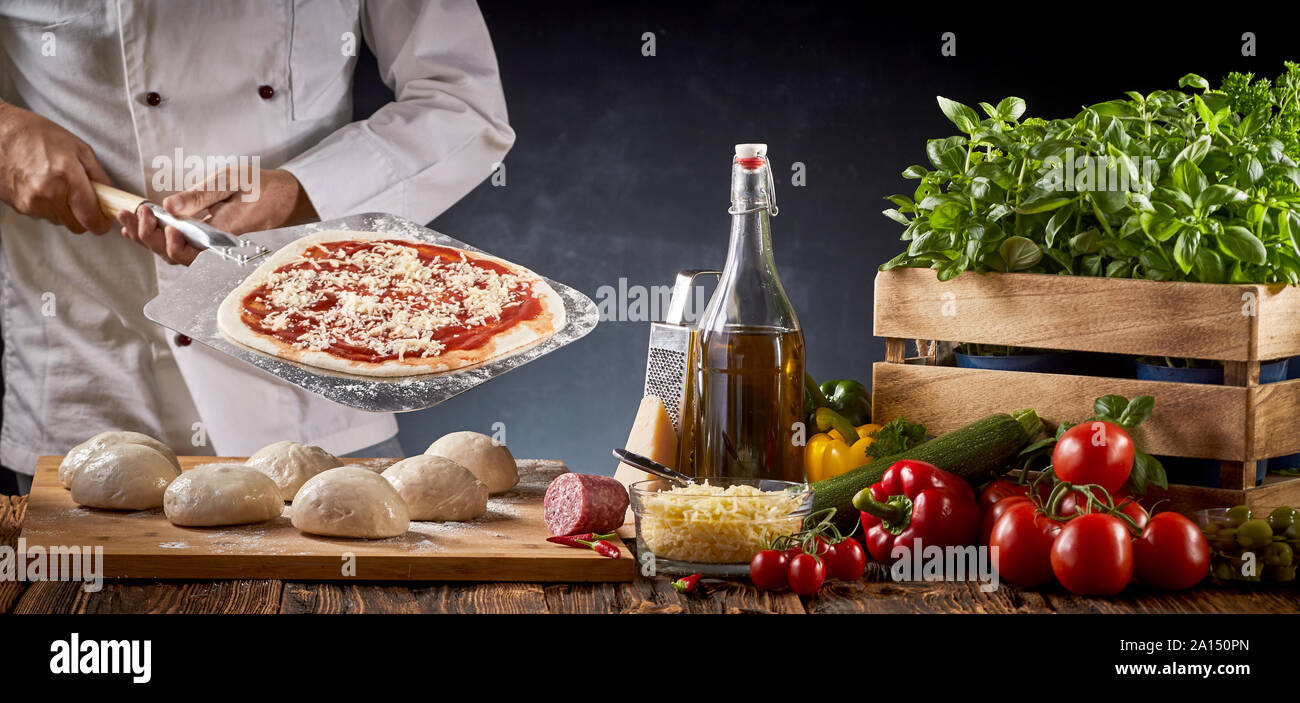 Chef at a restaurant making a traditional Italian pizza holding a base ...