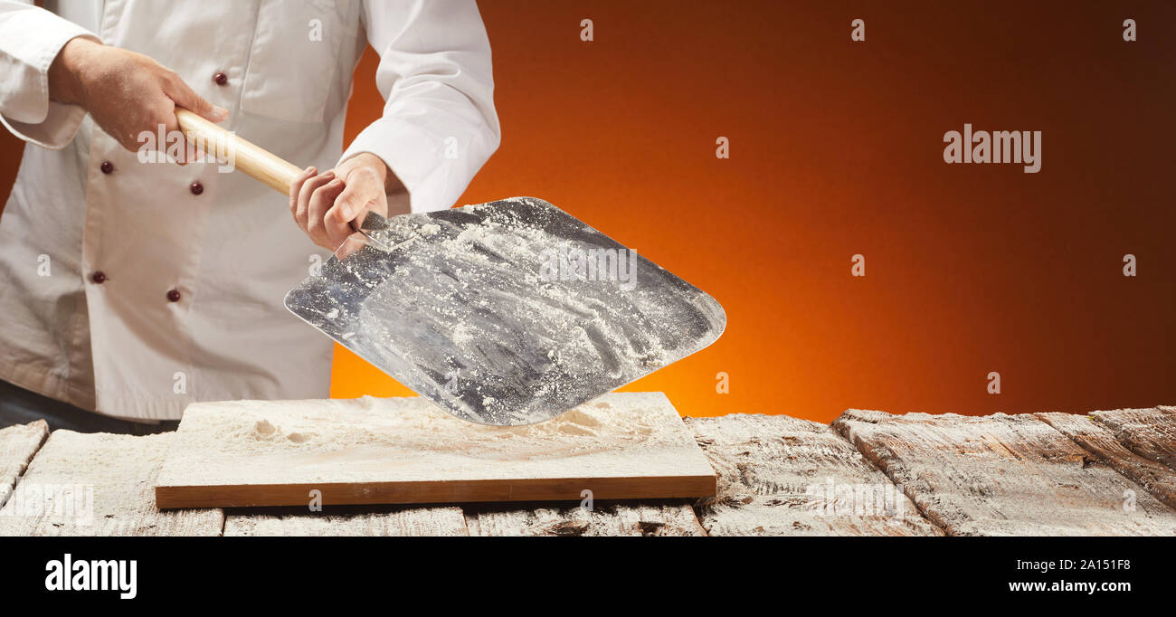 Chef holding a floured empty metal pizza paddle over an old rustic or ...