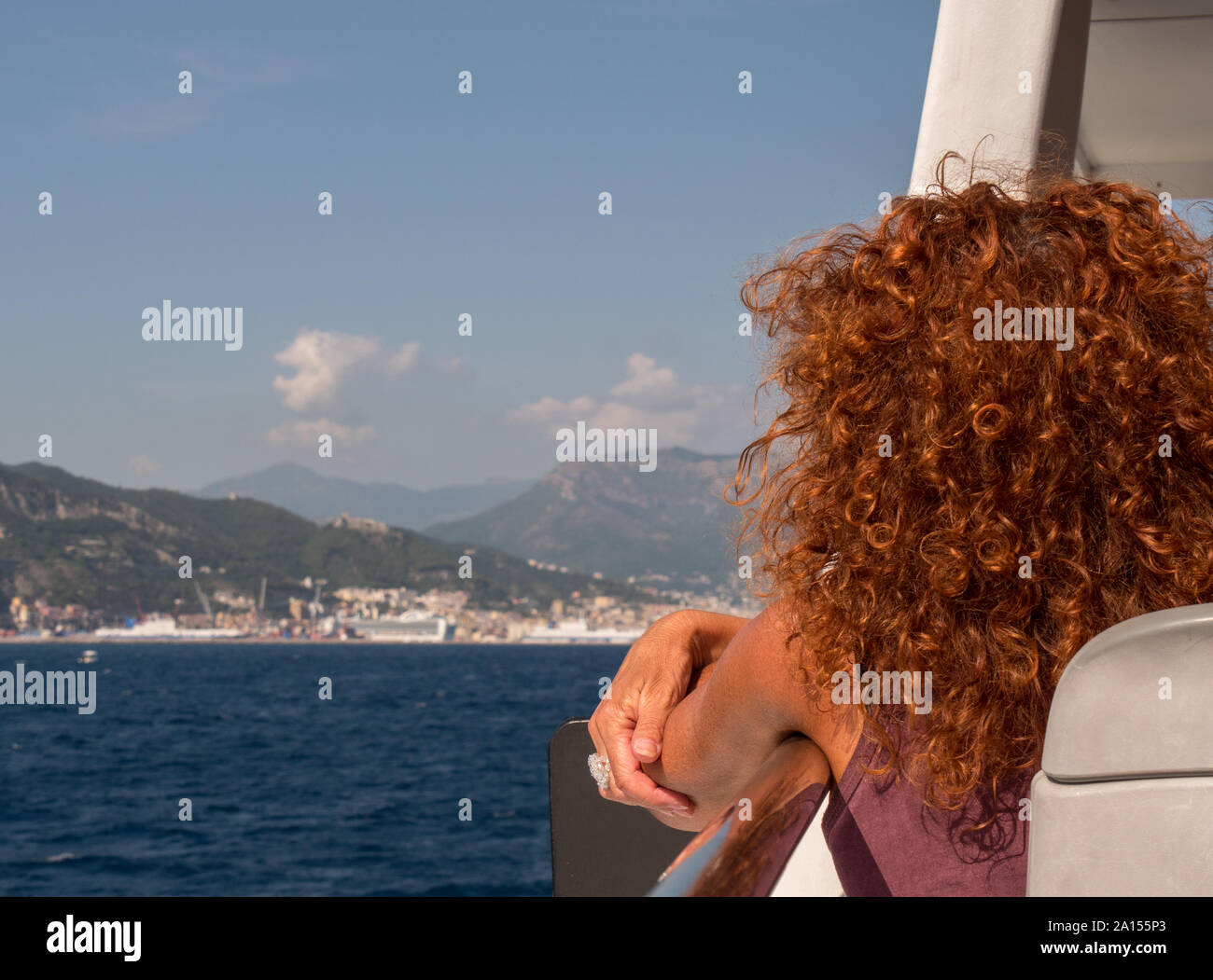 A woman with red curly hair leaning on the side of a boat Stock Photo ...