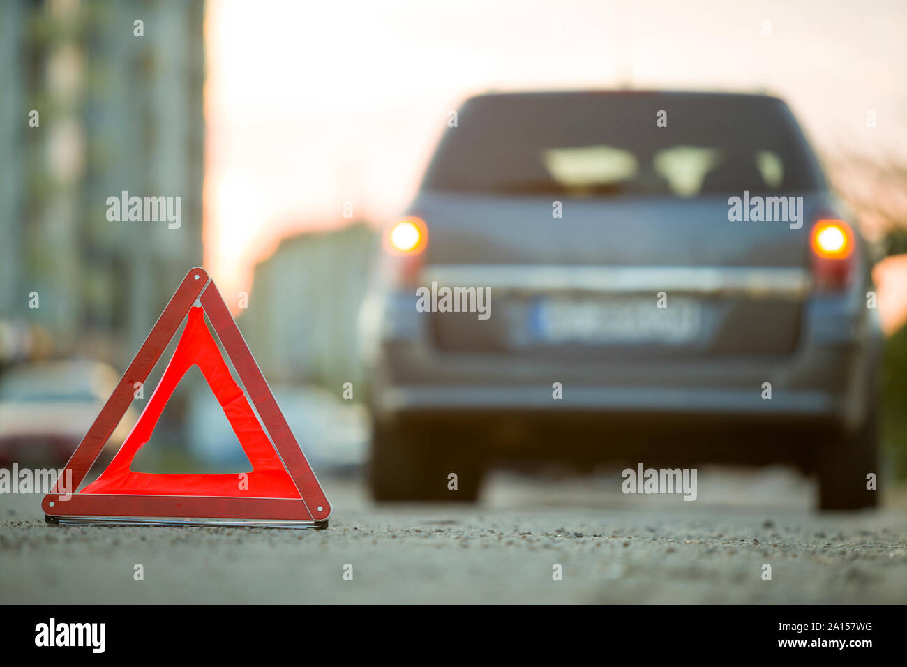Red emergency triangle stop sign and broken car on a city street Stock ...