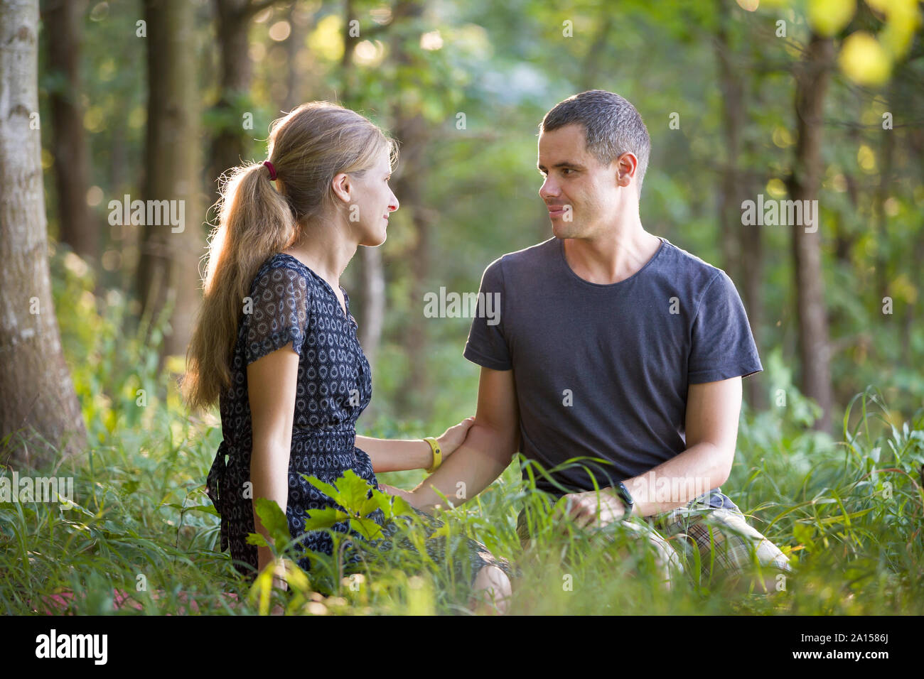 Youg couple, man and a woman sitting together outdoors enjoying nature ...