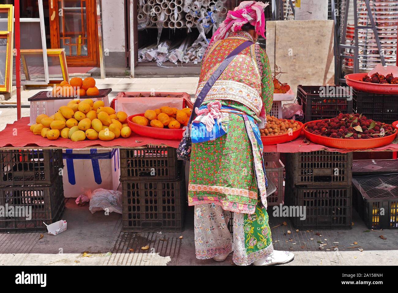 Local female Chinese ethnic merchant selling fruits at Friday flea ...