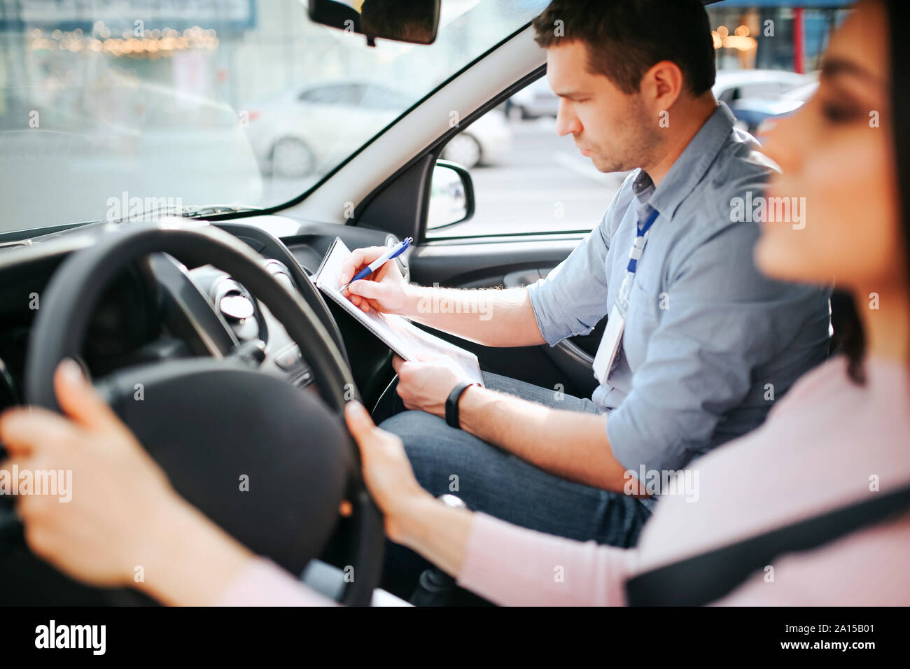 Male auto instructor takes exam in young woman. Model driving car. Hold ...