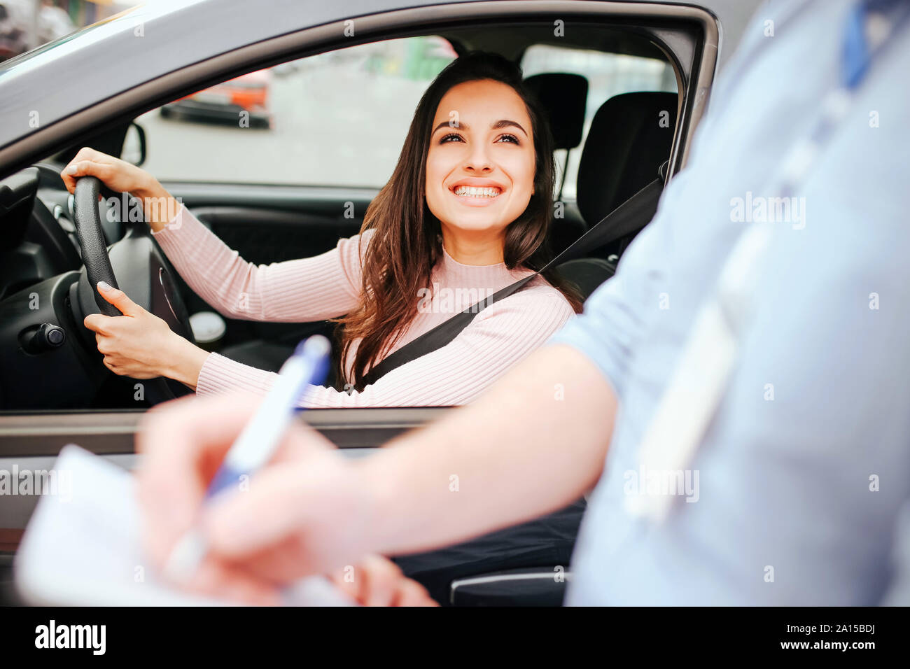 Male auto instructor takes exam in young woman. Cheerful attractive ...