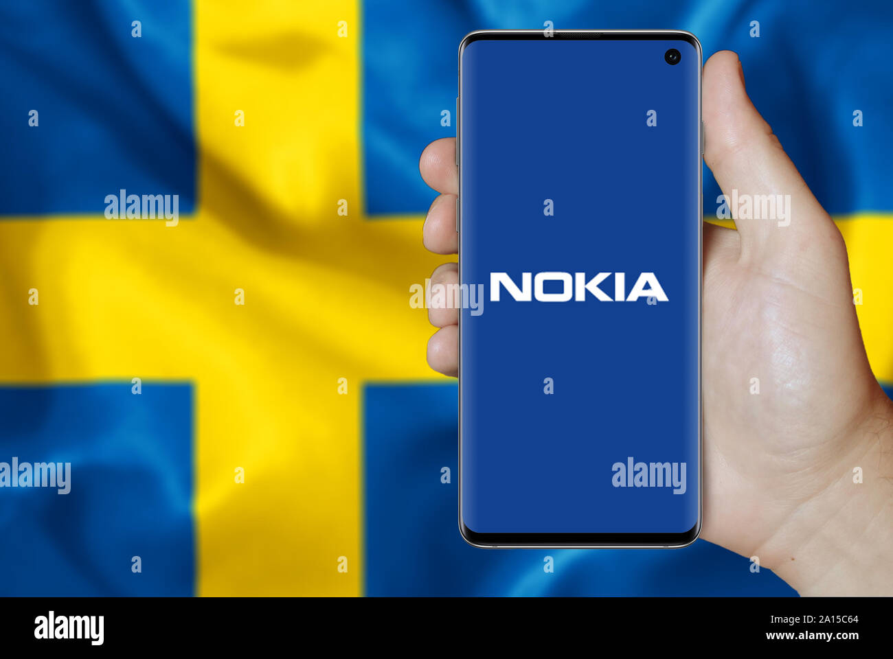 A man holds a smartphone displaying the logo of company Nokia listed on ...