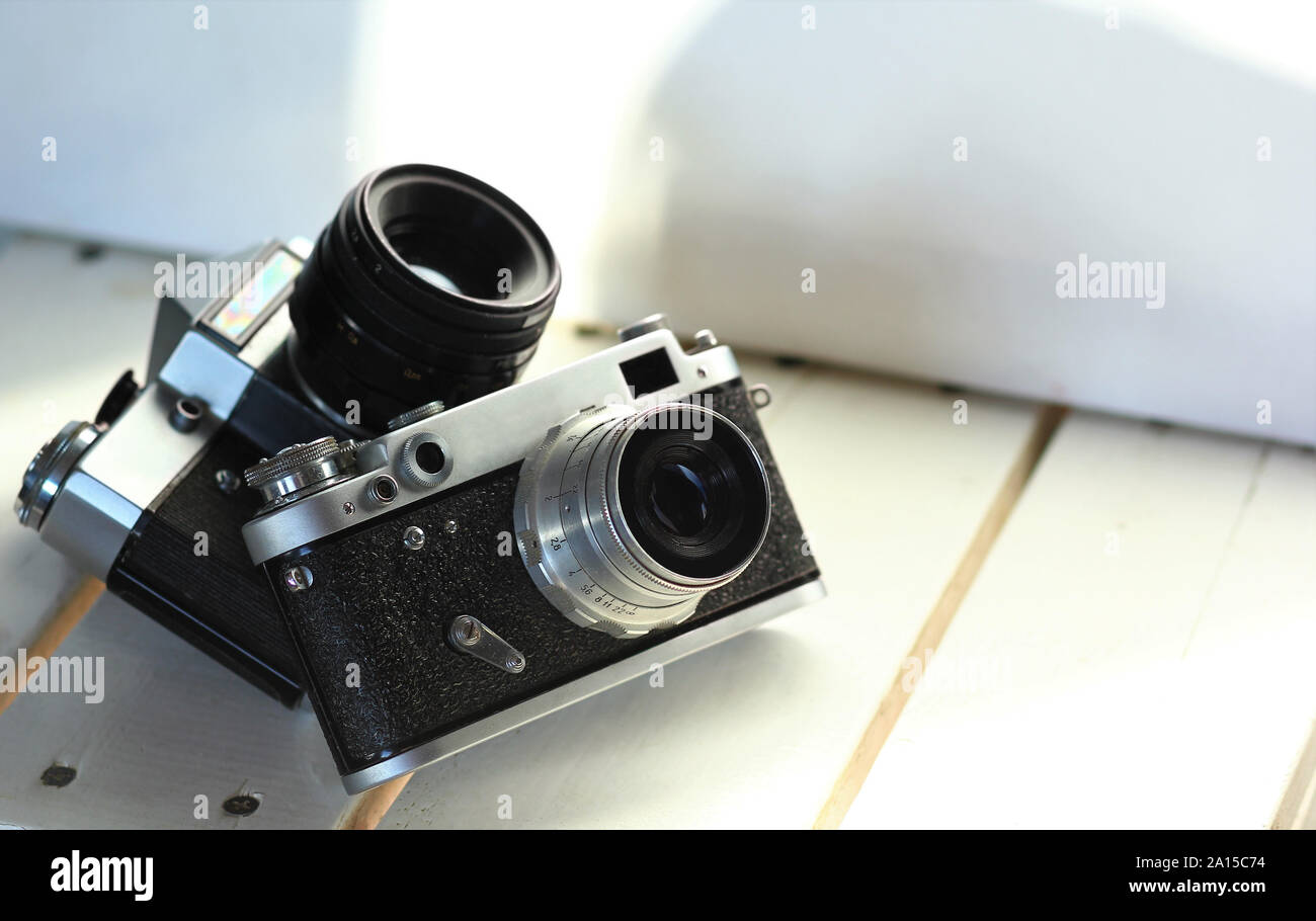 Two black old-school vintage film photo cameras on white wooden planks ...