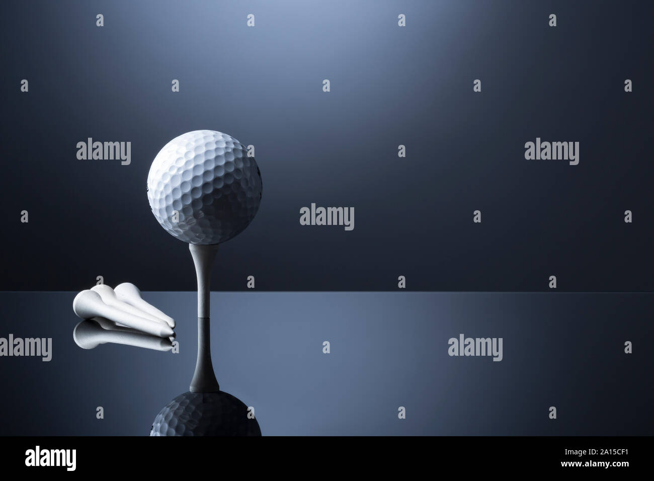 Golf ball on tee isolated on dark blue reflective background Stock ...