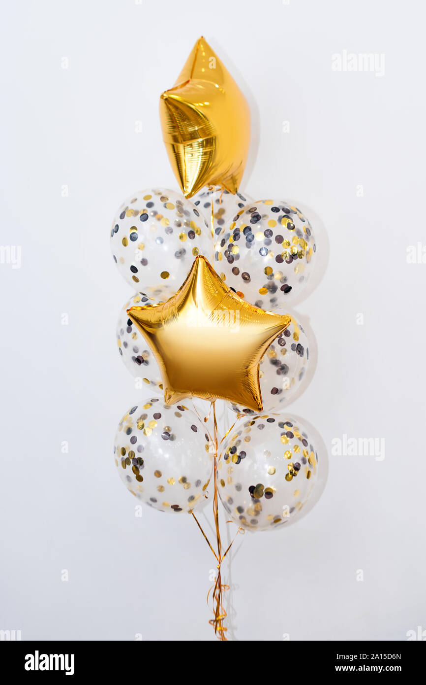 Metallic gold helium balloons of different shapes on white background ...
