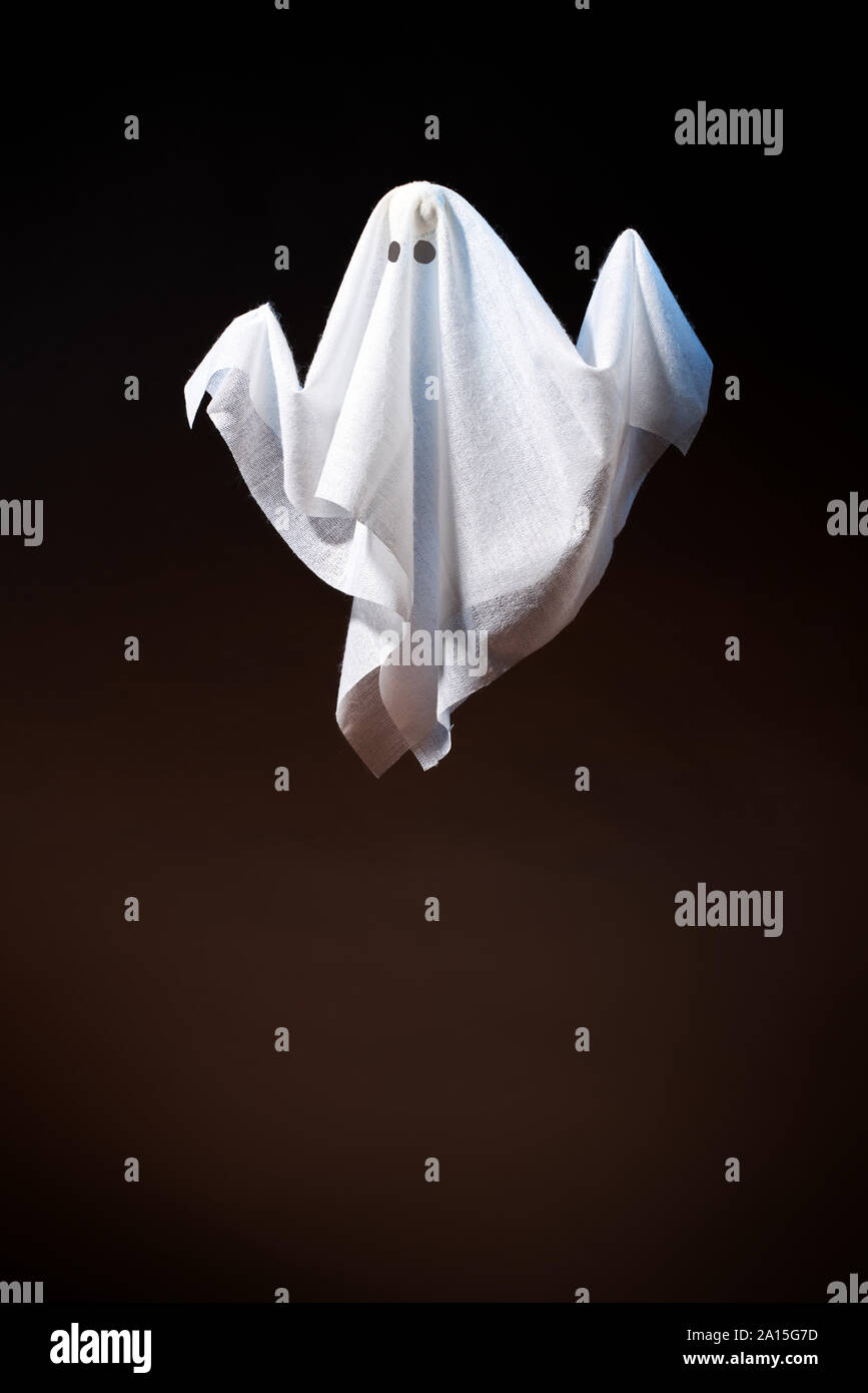 Photo of halloween ghosts made of white fabric on empty black ...