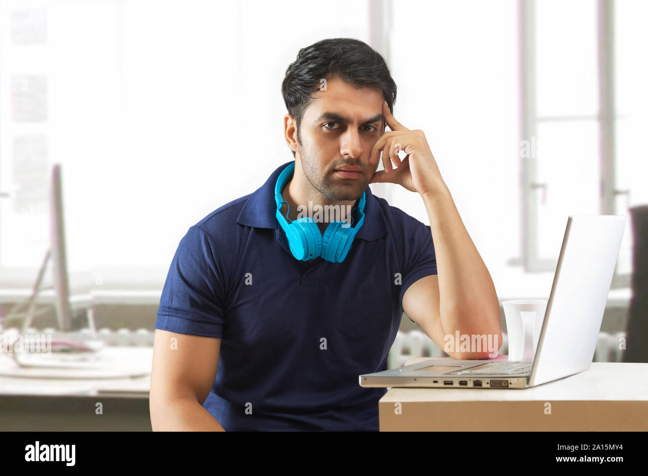 Young guy working in office using headset and laptop hand rests on the ...