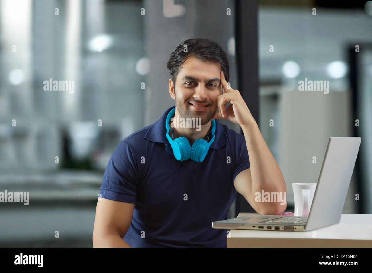 Young guy working in office using headset and laptop hand rests on the ...